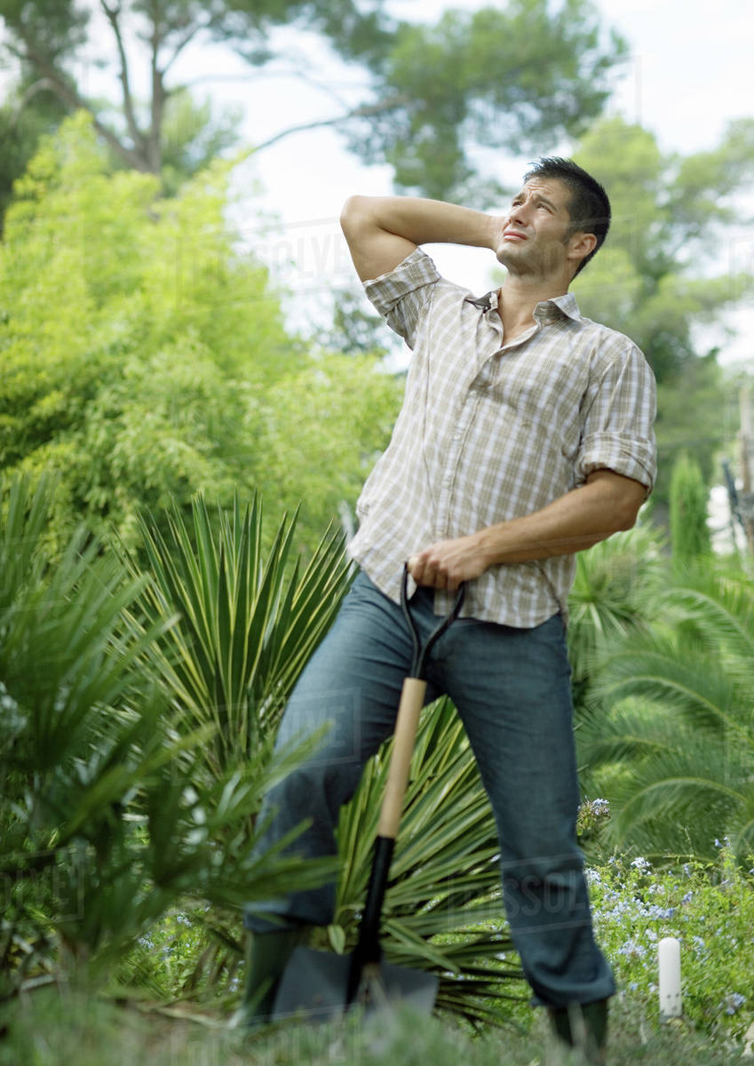 Man holding shovel, hand behind head, looking up - Royalty-free Stock ...