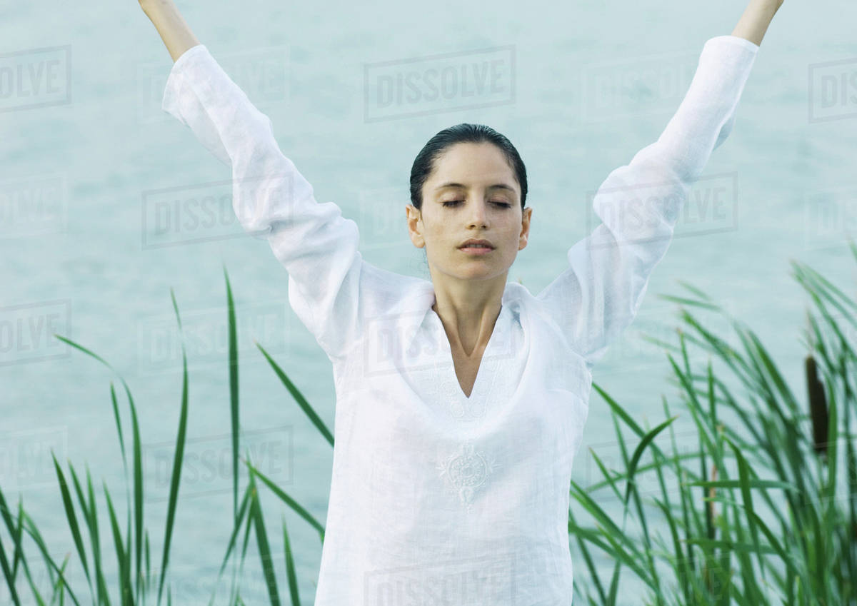 Woman stretching arms over head, lake in background - Royalty-free ...