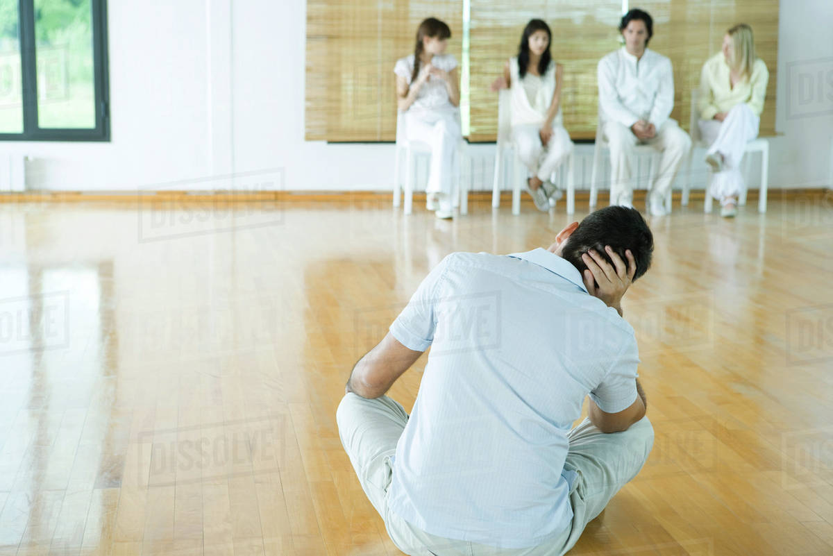 Man sitting on floor, facing group sitting in chairs - Royalty-free ...