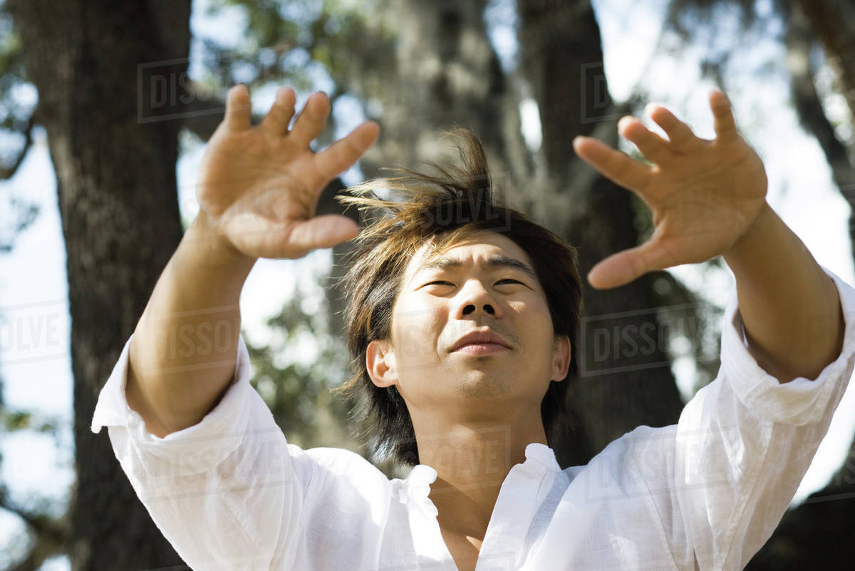 Man standing with arms out in front of him while breeze blows, low ...