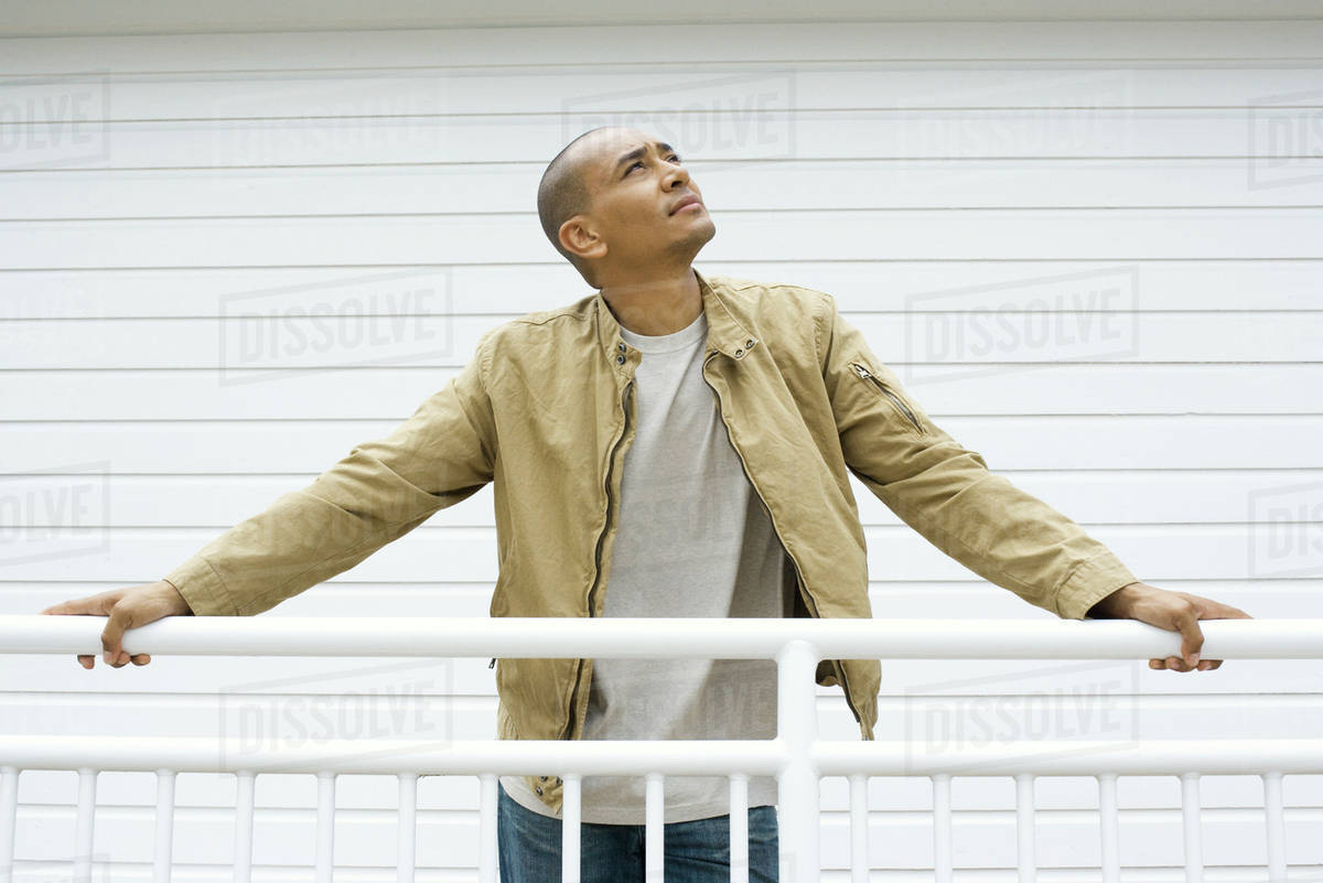 Man holding on to railing, looking up - Royalty-free Stock Photo | Dissolve