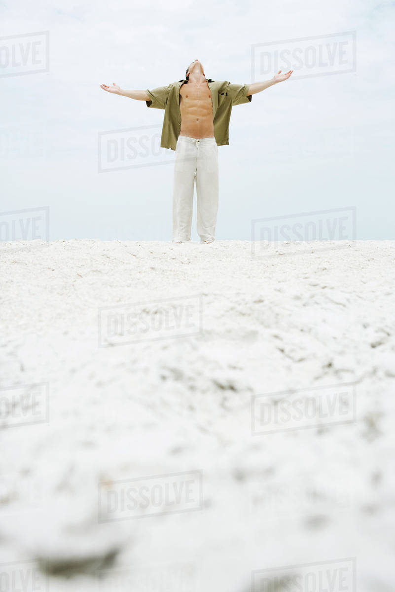 Man standing at the beach with arms out, head back - Stock Photo - Dissolve
