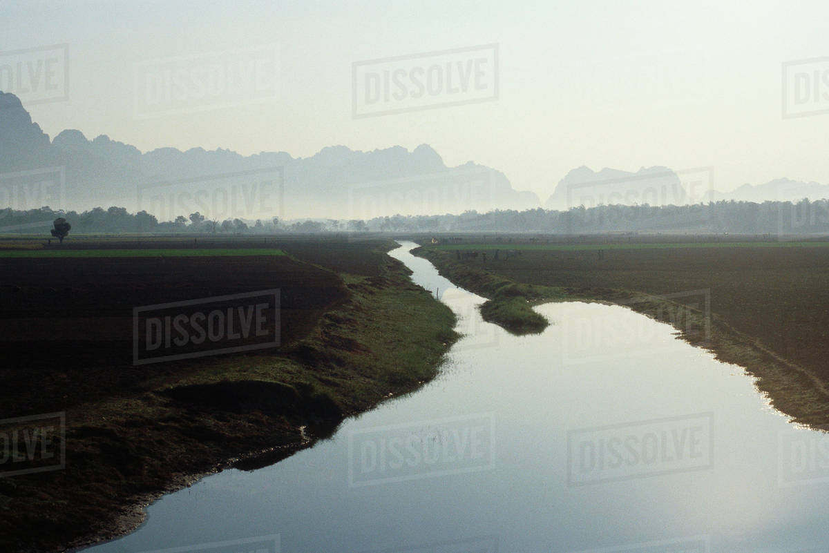Myanmar (Burma), landscape with fields and irrigation ditch, mountains ...