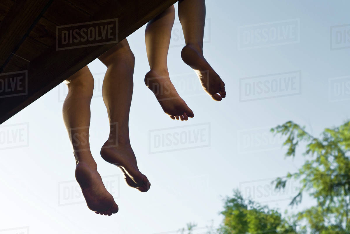Adult and child sitting on deck with legs dangling off edge, cropped ...