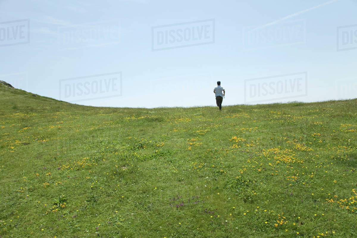 Man running through meadow - Stock Photo - Dissolve