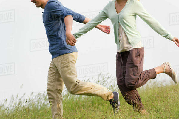 Couple holding hands running on meadow, cropped - Royalty-free Stock ...