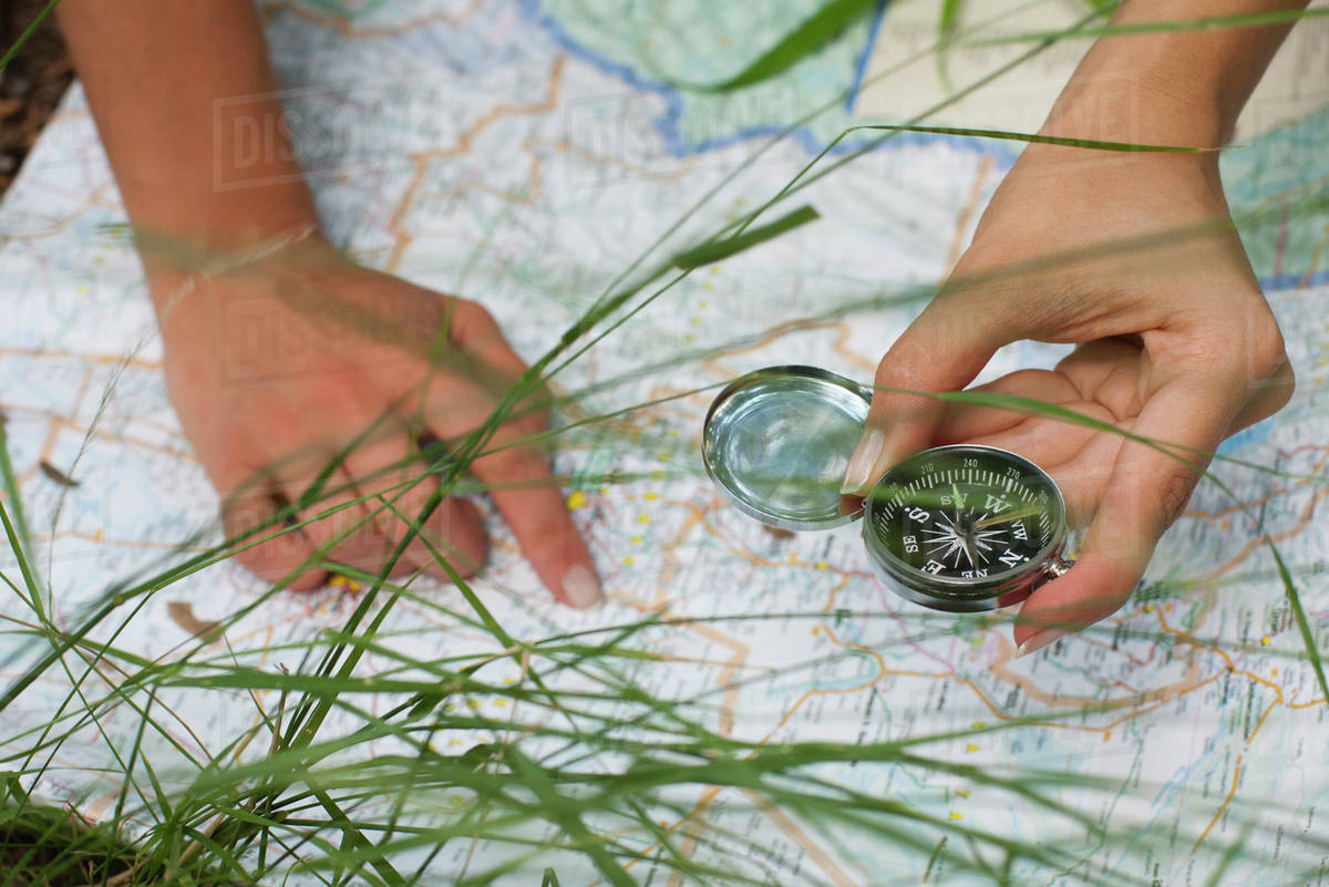 Woman using compass and map outdoors, cropped - Stock Photo - Dissolve