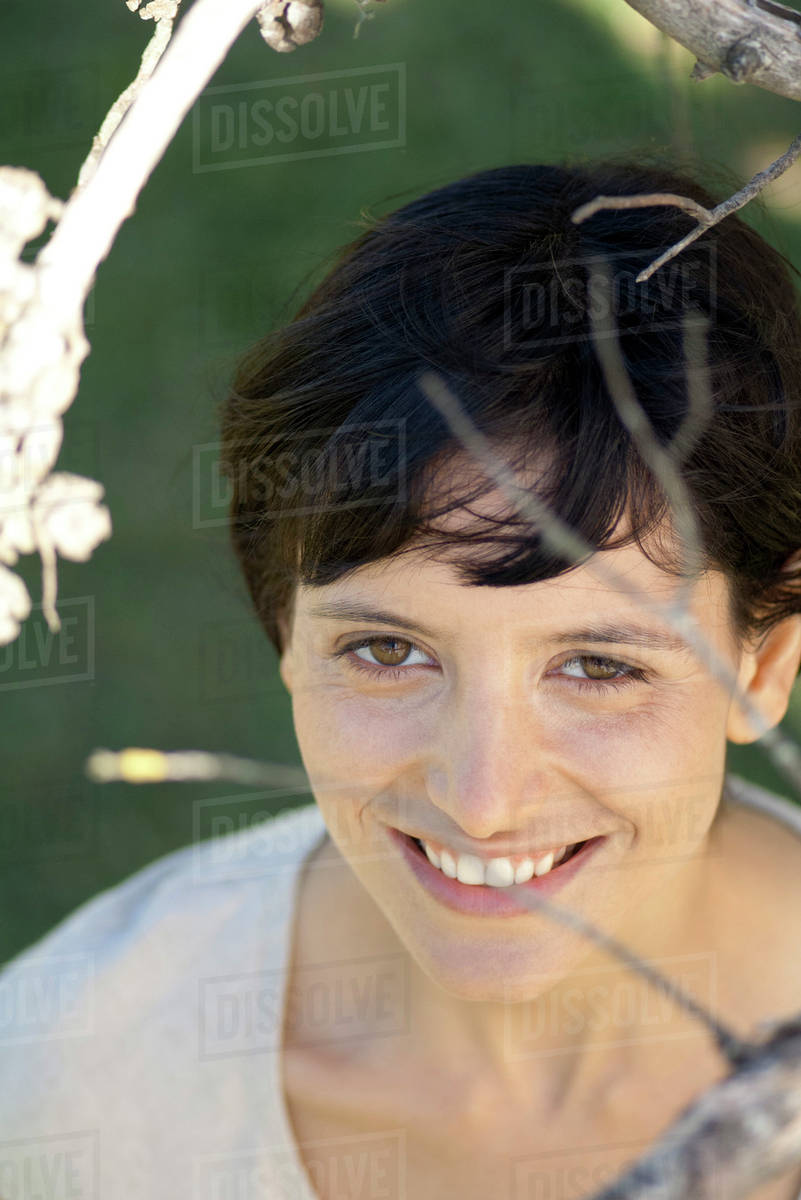 Young woman smiling through tree branches, portrait - Royalty-free ...