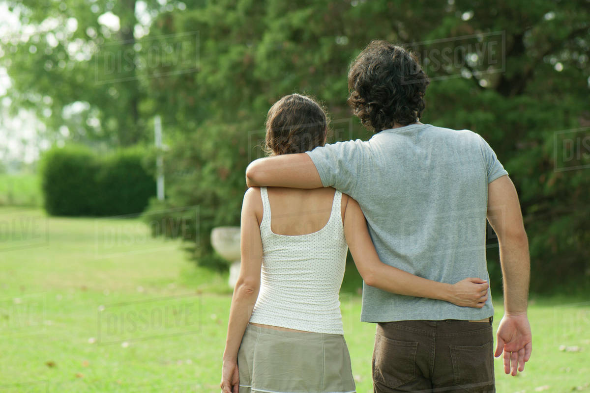 Couple walking together in park, rear view - Stock Photo - Dissolve