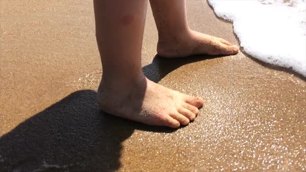 Child feet walking by beach shore. Waves crash on toddler feet. Kid ...