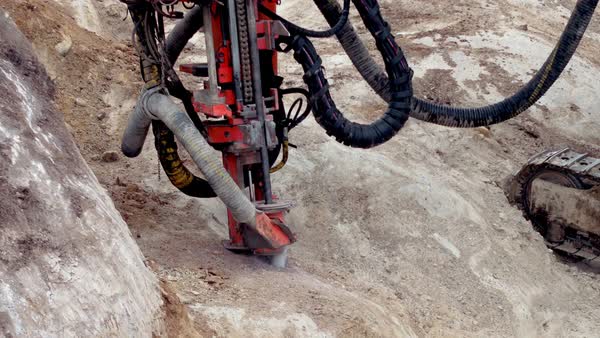 Tophammer drill rig drilling hole in rocks - Stock Video Footage - Dissolve