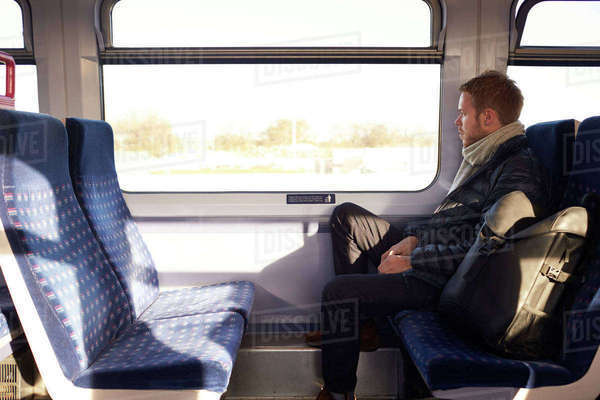 Young man sitting in train carriage on railway journey - Royalty-free ...