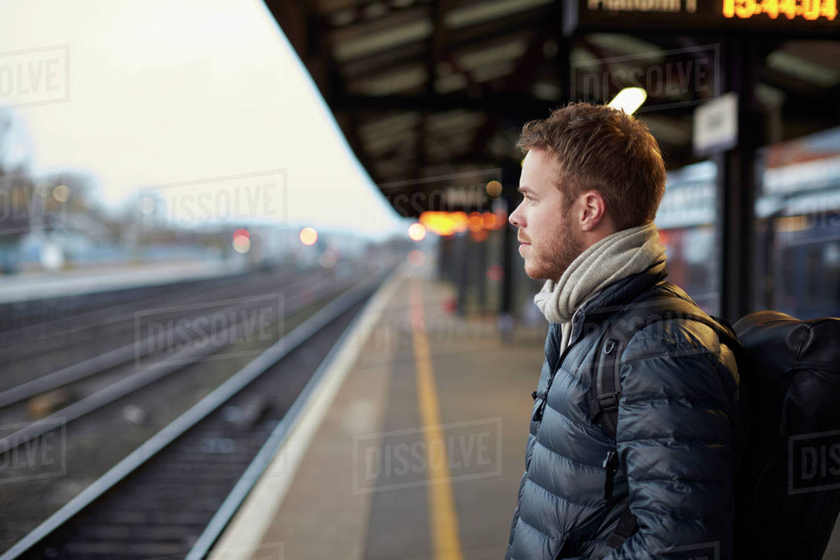 Man standing on railway platform waiting for train to arrive - Stock ...