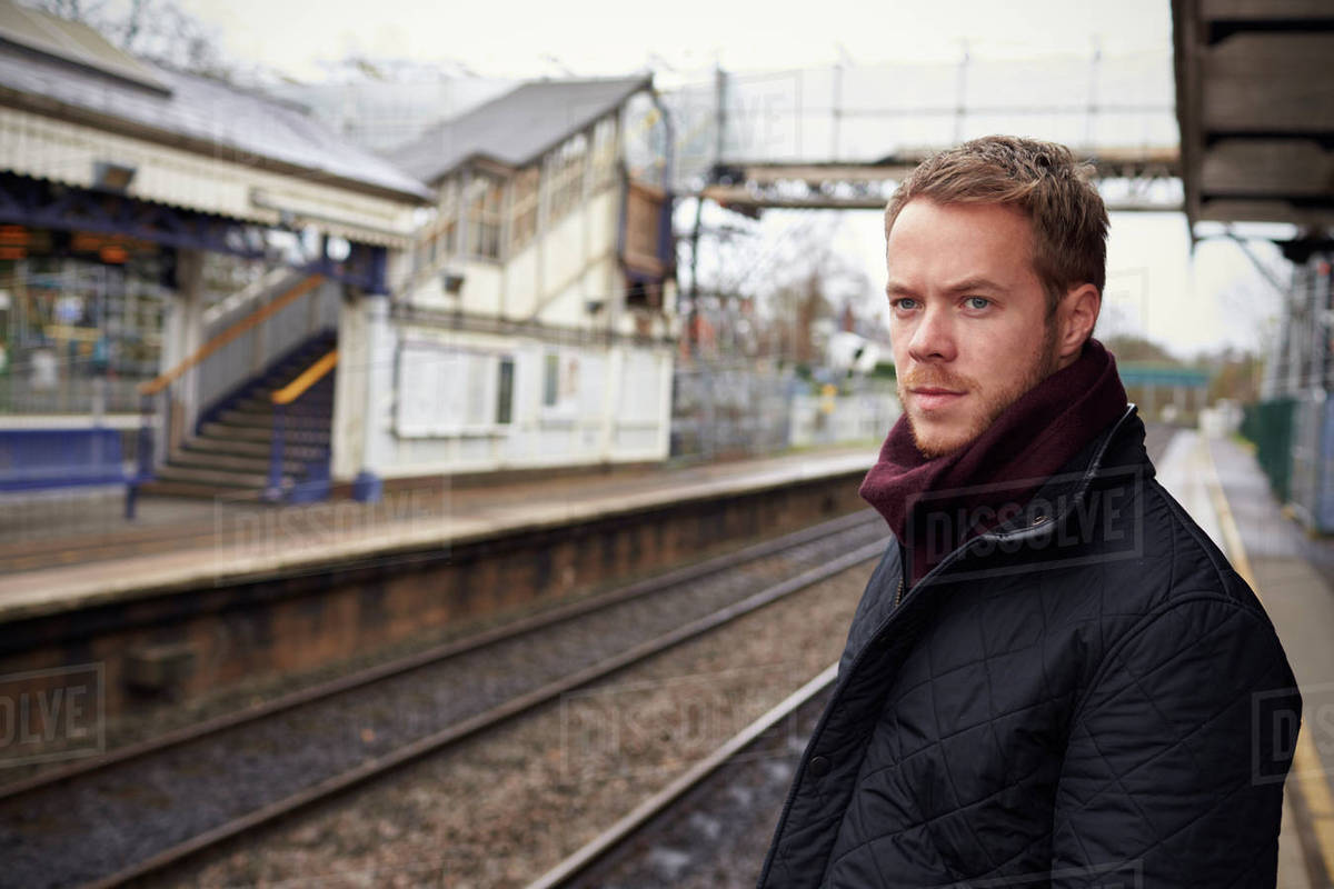 Man standing on railway platform waiting for train to arrive - Royalty ...