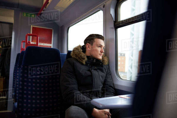 Young man sitting in train carriage on railway journey - Royalty-free ...