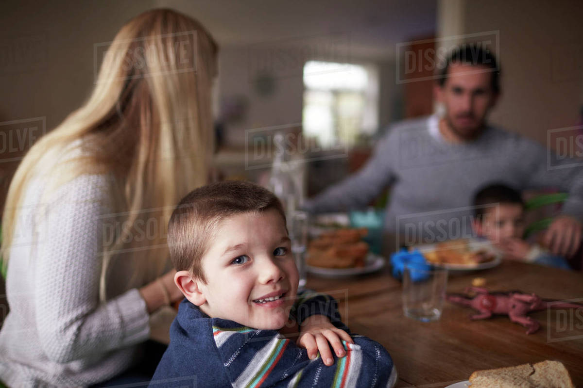 Family sitting at kitchen table and eating meal together - Royalty-free ...