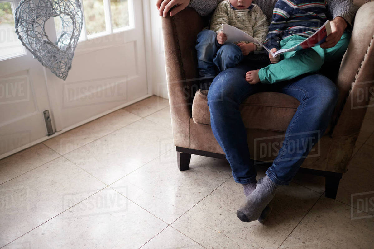 Father sitting in chair at home reading story to sons - Royalty-free ...