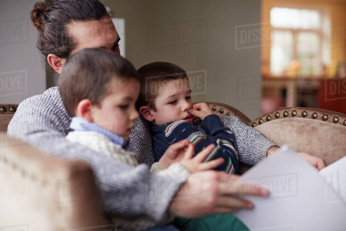 Father sitting in chair at home reading story to sons - Royalty-free ...