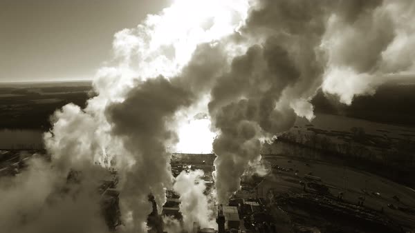 Factory smokestacks, steaming and smoking, stunningly back-lit by the ...