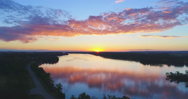 Fiery sunrise over vast river valley, calm waters reflecting dramatic ...