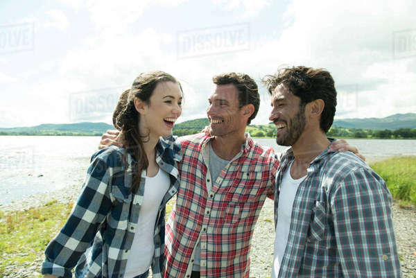 Three friends standing smiling on the shore of Bala Lake in Wales ...
