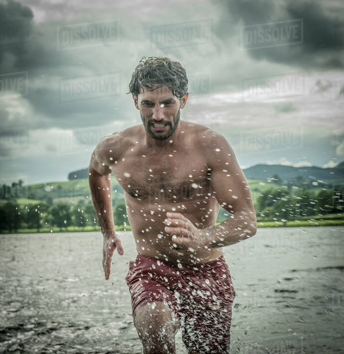 A fit man running through the shallow water of Bala Lake in Wales ...