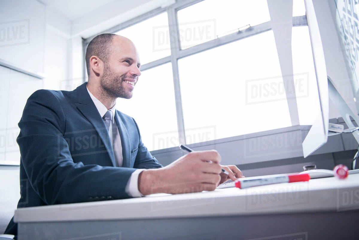A professional man sitting in front of a computer in an office ...
