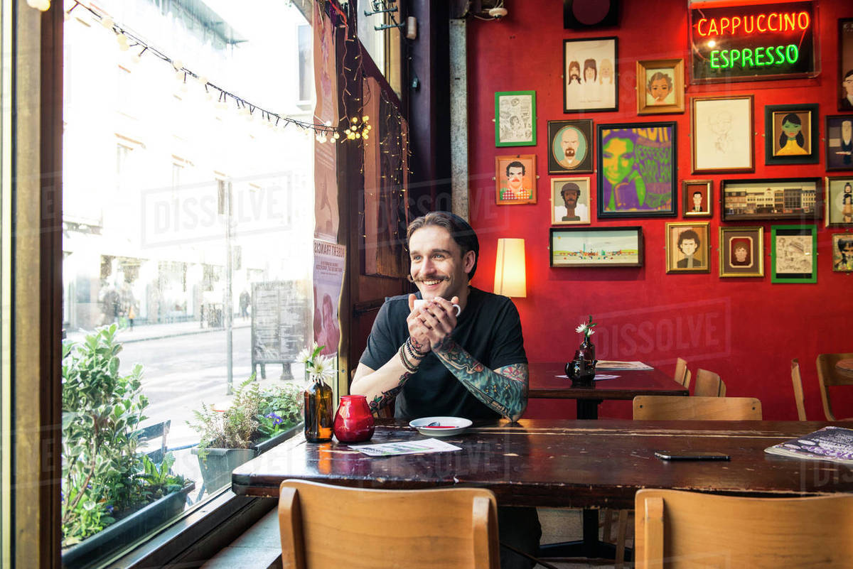 A young man sitting at a table in a coffee shop in Manchester - Royalty ...