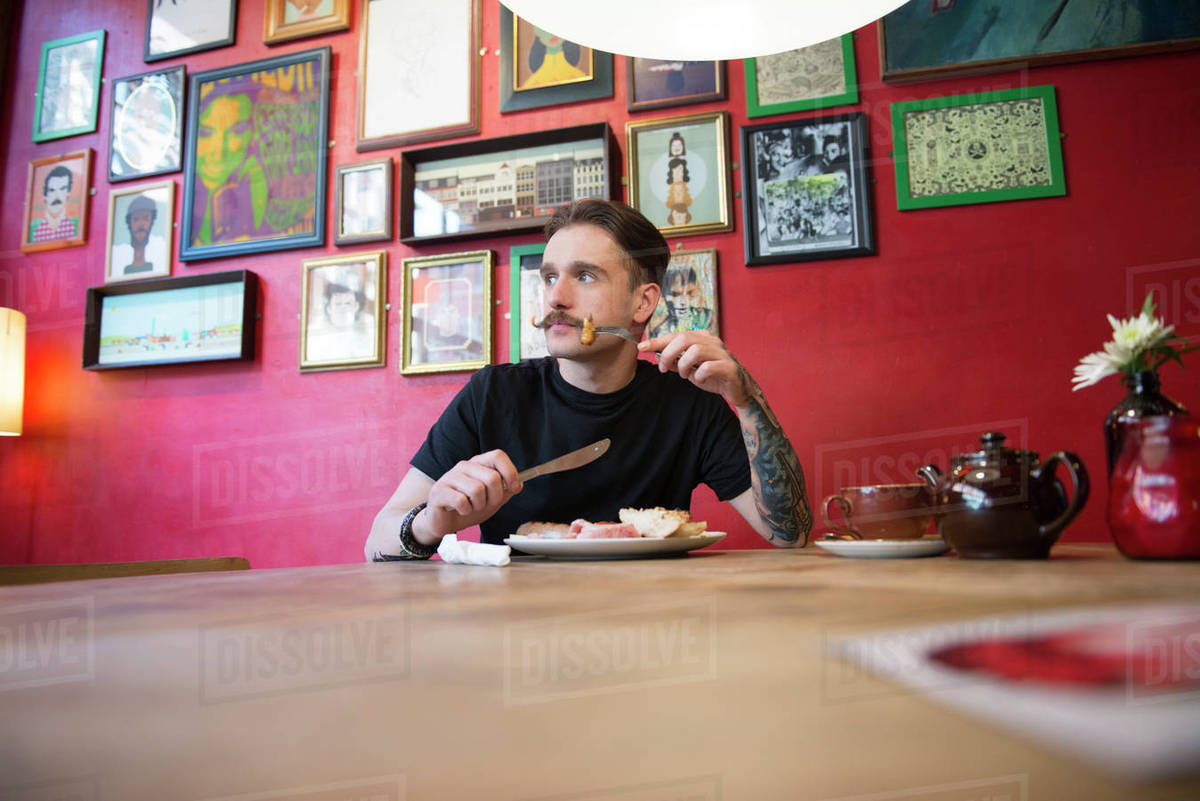 A young man eating at a table in a coffee shop in Manchester - Stock ...