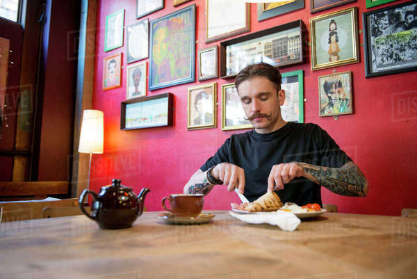 A young man eating at a table in a coffee shop in Manchester - Royalty ...