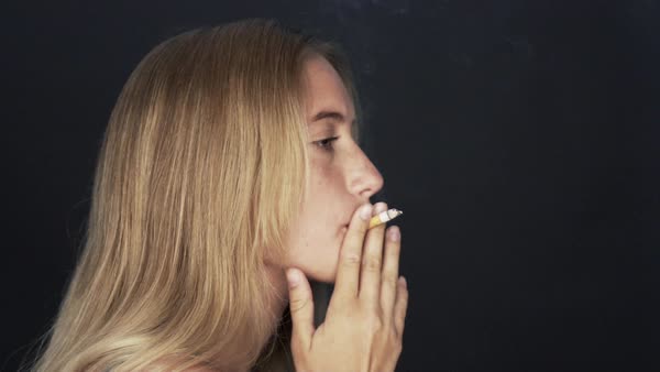 Young woman smoking cigarette turning and smiling over shoulder - HD ...