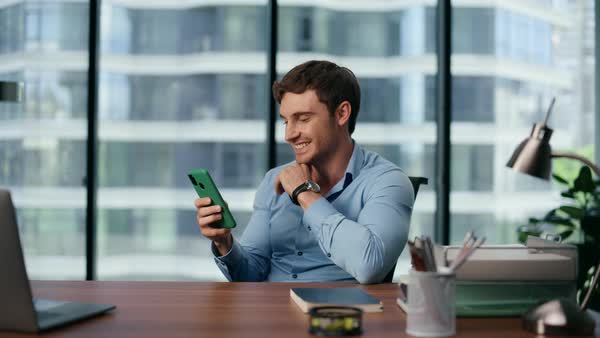 Laughing boss reading smartphone message office. Man smiling looking ...