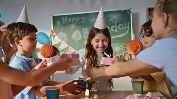 Children congratulating birthday girl giving gift boxes closeup. Happy ...