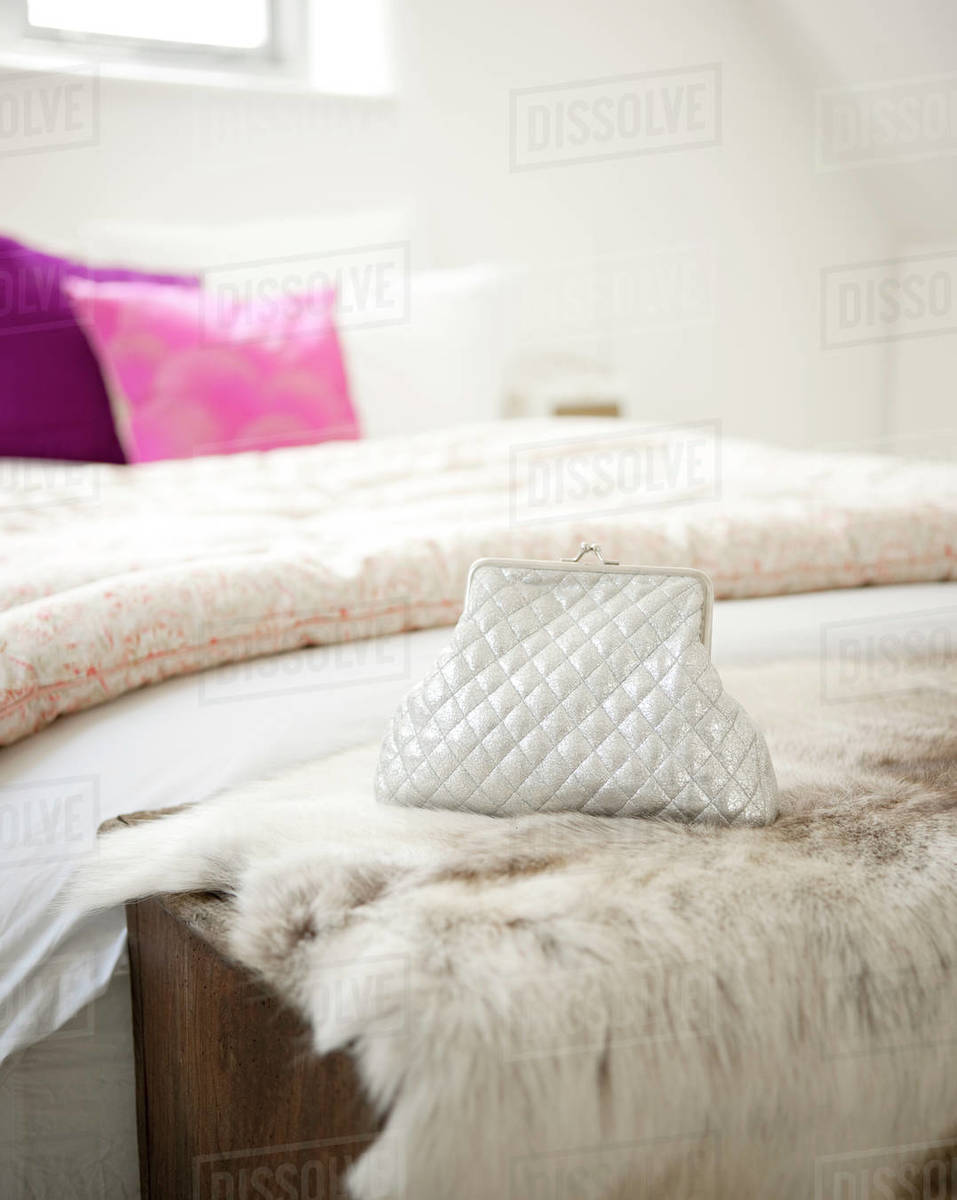 Silver purse at foot of bed in bedroom of cottage interior, UK. - Stock ...