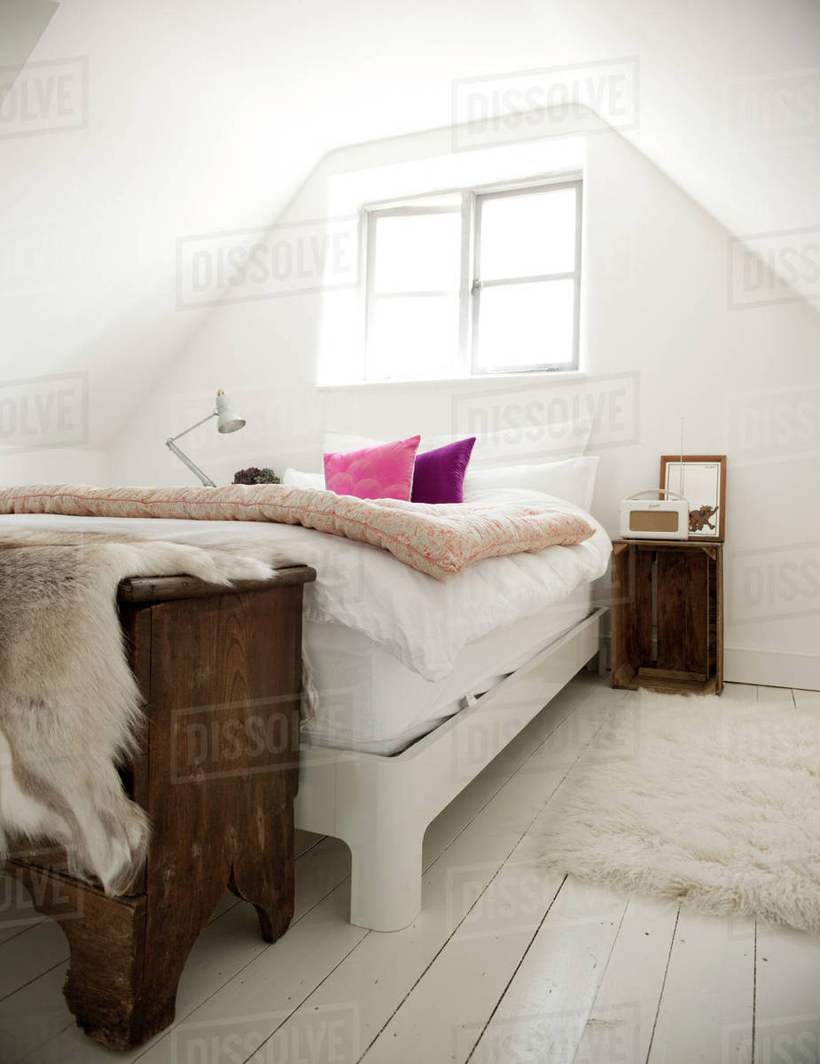 Bed below window in cottage interior, UK. - Stock Photo - Dissolve
