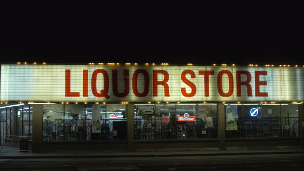 Wide shot of liquor store sign hanging outside the shop at night, Las ...