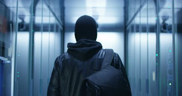 Medium, slow motion shot from behind of a hacker with a backpack ...