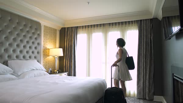 Young woman walking into a hotel room and pulling curtains open - 4K ...