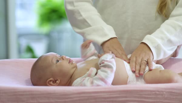 Mother changing baby daughter's diaper, panning left, surface level ...