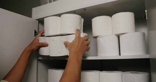 Stocking piles of toilet paper inside the storage cabinet at home ...