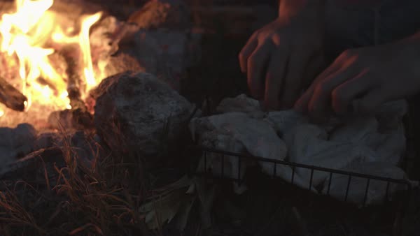Evening in campfire, man hands placing chicken on grill grids, cooking ...