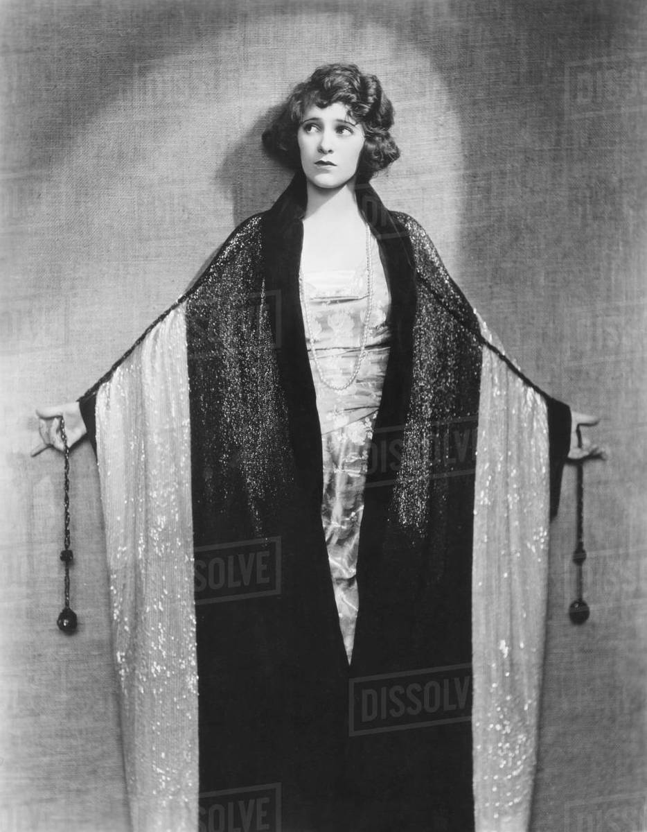 Spotlight on woman in a beaded robe with her arms outstretched ...