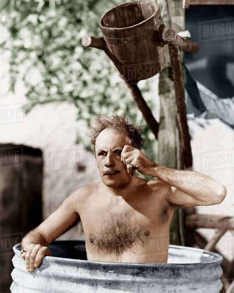 Man sitting in a barrel taking a bath and looking through his monocle ...