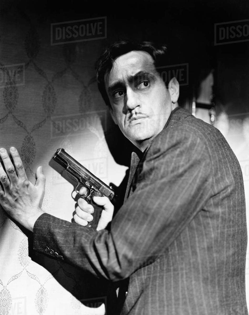 Profile of a gangster holding a handgun looking over his shoulder ...