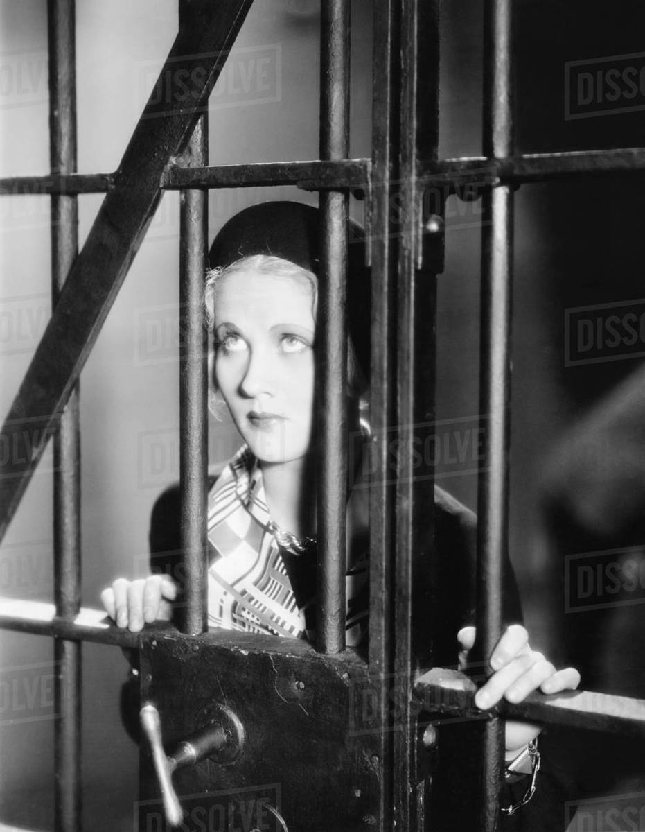 Young woman standing behind bars in a prison cell - Royalty-free Stock ...