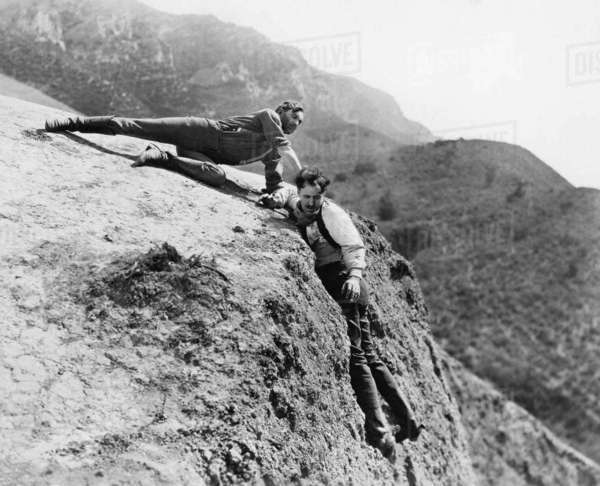 Man helping another man from falling down a cliff - Royalty-free Stock ...