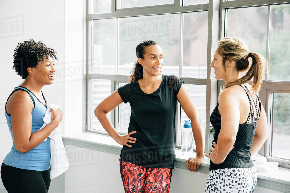 Friends relaxing near window after workout - Stock Photo - Dissolve