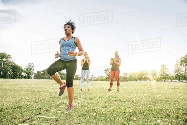 Friends encouraging woman running ladder in field - Royalty-free Stock ...