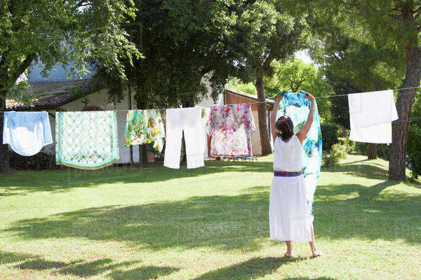 Caucasian woman hanging laundry on clothes line - Stock Photo - Dissolve