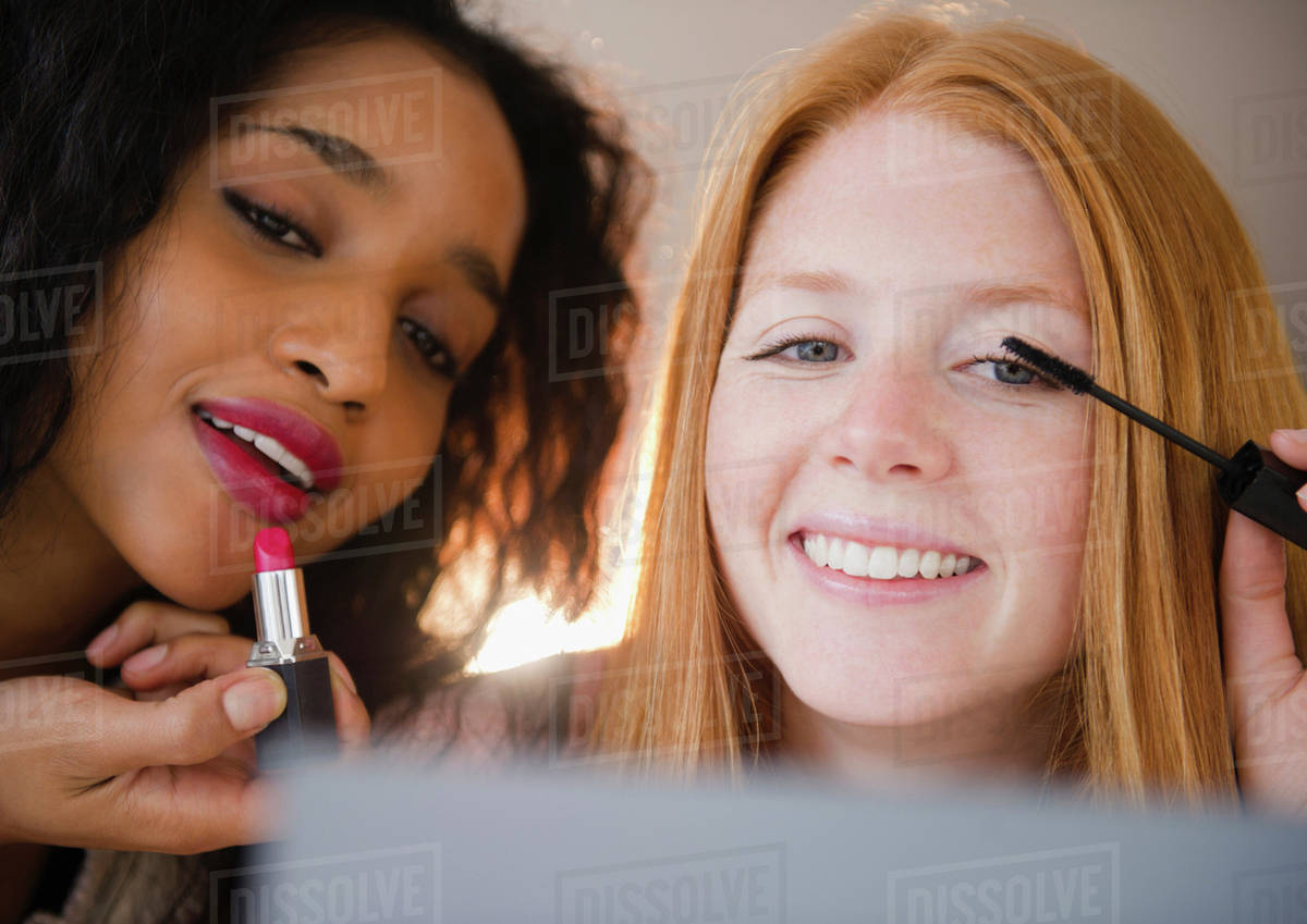 Smiling woman putting on makeup - Stock Photo - Dissolve